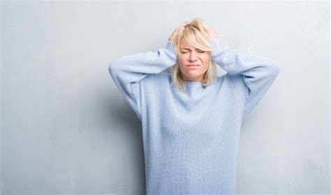 그런 지 회색 벽 때문에 두통 절망과 스트레스에서 고통 겨울 스웨터를 입고 이상 성인 백인 여자 통증과 편두통 머리에 손입니다