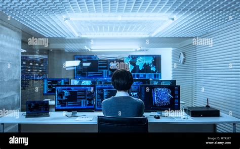 Back View Of The It Engineer Working With Multiple Monitors Showing