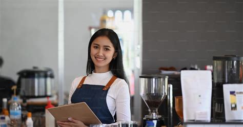 성공적인 중소기업 소유주는 미소 지으며 커피 숍의 카운터 뒤에 서 있습니다 사진 Unsplash의 카페 이미지