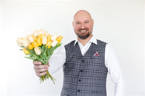 회색 조끼를 입고 웃는 중년 사업가의 초상화 흰 셔츠를 들고 노란 튤립의 꽃다발을줍니다 휴일 35 39세에 대한 스톡 사진 및
