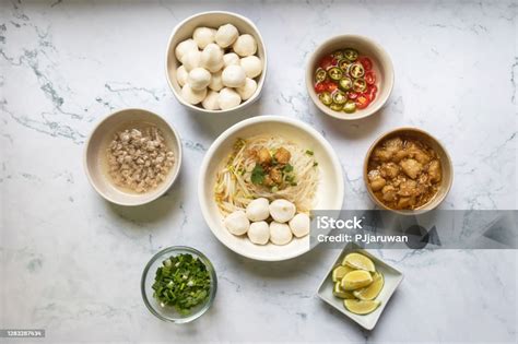 흰 그릇에 생선 공을 곁들인 쌀 스틱 국수 라드 다진 돼지고기 절인 칠리 라임 고수와 함께 봄 양파를 곁들인 마늘 딱딱거리는 마늘과 식탁에 조미료를 얹습니다 건강한 생활