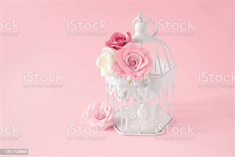 분홍색 배경에 고립 된 꽃으로 장식 된 흰색 새장 공간을 복사합니다 결혼식과 생일 발렌타인 데이의 날인사의 개념 개념에 대한