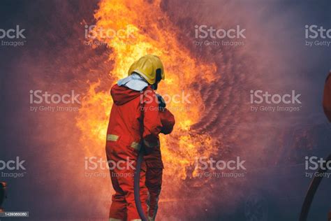 소방관 소방 소화기에서 구조 훈련 소방 호스 화학 물 거품 스프레이 엔진을 사용하여 화염으로 싸우는 소방관 소방관은 보호를 위해 단단한 모자 안전 복 유니폼을 착용합니다