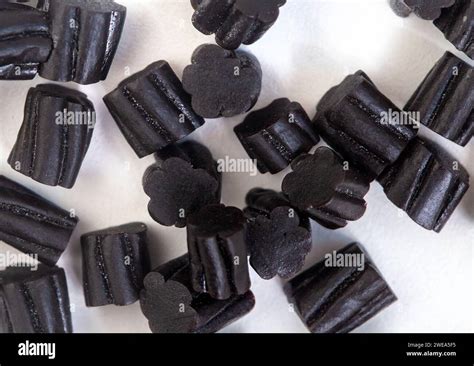 Pieces Of Black Licorice Sweets Scattered On Plain White Surface Stock