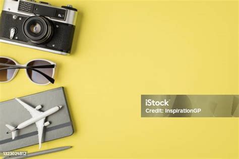 카피 스페이스가있는 고립 된 파스텔 노란색 배경의 회색 노트북에서 카메라 선글라스 펜과 비행기 모델의 상단 보기 사진 0명에