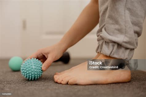 마사지 볼을 사용하여 평발 교정 체조 운동을 하는 여성 발 근육의 근막 이완 환각 외반 통증이 있습니다 평발의 식별 가정에서의 자기 관리 관행 건강 관리 발 마사지 마사지에