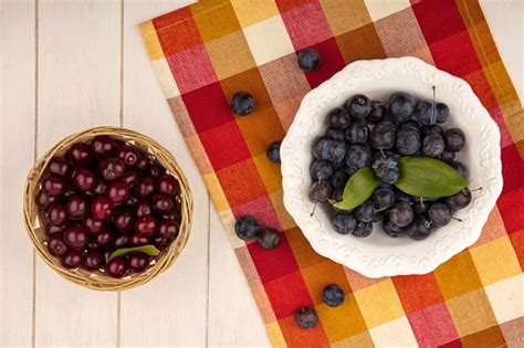 흰색 배경의 양동이에 빨간 체리를 곁들인 체크 무늬 식탁보에 흰색 그릇에 작은 신맛이 나는 파란색검은색 과일 슬로의 평면도 0명에 대한 스톡 사진 및 기타 이미지 Istock