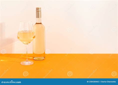 Bottle And Glass Of White Wine On Begie And Orange Background With Deep
