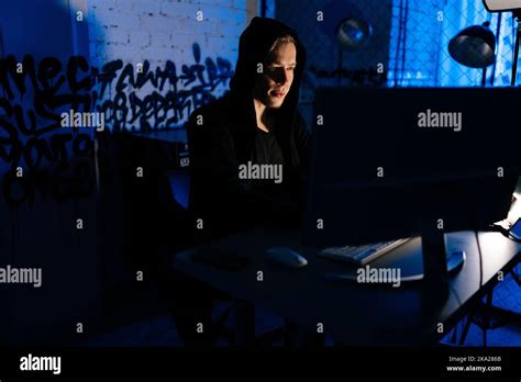 Medium Shot Portrait Of Hidden Hacker Man Wearing Sweatshirt With Hood Engaged In Hacking Into