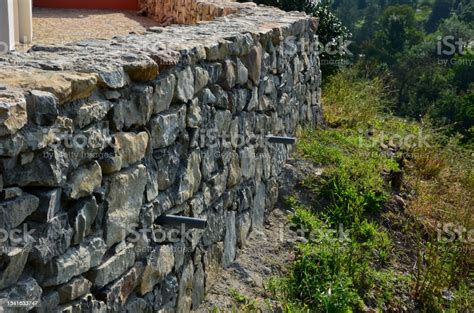 시멘트 박격포와 결합 거친 돌의 아름답게 접힌 옹벽 갈색 베이지 색 노란색 불규칙한 석회암 돌 그 위에 경사를 들고 물 배수 파이프는 벽에서 멀리 리드 옹벽에 대한 스톡