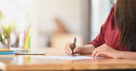 종이에 글을 쓰고 나무 작업 책상에 앉아 있는 동안 여자 빨간 셔츠의 측면 사진 사진 Unsplash의 테이블 이미지