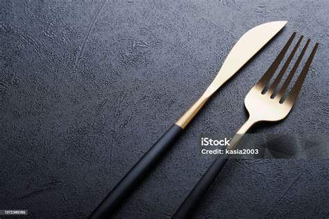 골드 스푼 포크 칼 깨끗한 빈 검은 접시 블랙 백에 세련된 블랙과 골드 칼의 세트 유행과 고급 식사 맨 위 보기입니다 텍스트의 공간을 복사합니다 0명에 대한 스톡 사진 및