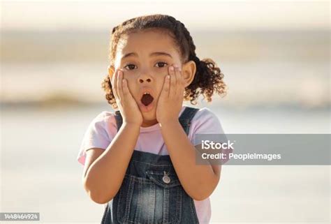 와우 아이들과 손은 여름에 밖에서 놀랐거나 충격을 받은 해변에서 소녀의 얼굴에 있습니다 어린이 청소년 및 혼자 야외에서 충격을 느끼는 작은 여자 아이와 함께 놀라움 아이에
