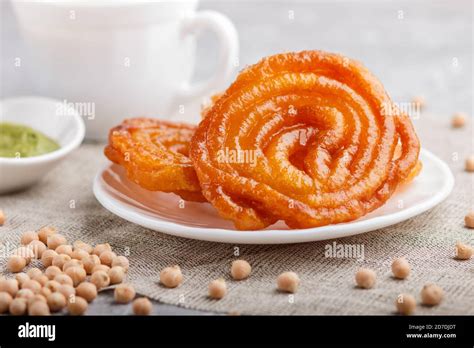 Traditional Indian Candy Jalebi In White Plate With Mint Chutney On A Gray Concrete Background