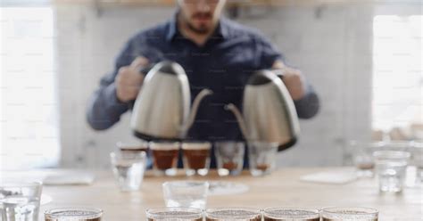 남성 바리스타가 주전자 두 개에서 분쇄한 커피와 함께 유리 컵에 끓는 물을 쏟아내고 신선한 커피를 끓여 시음하는 모습을 클로즈업합니다 선택적 초점의 인물 사진 사진