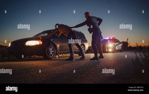A Professional Middle Aged Policeman Performing A Pat Down Search On A