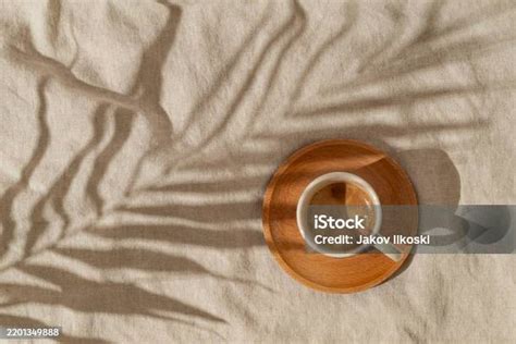 커피 한 잔과 열대 야자수 잎 그림자로 만든 여름날 풍경 모래 색 린넨 배경 태양과 그림자 최소한의 여름 커피 컨셉입니다 플랫 레이 스타일 상의 모습 커피 마실 것에 대한