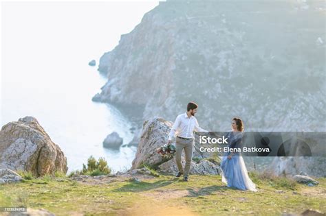 젊은 웨딩 커플입니다 패션 웨딩 드레스에 아름 다운 신부 키스와 아름 다운 풍경에 바위 근처 포옹 결혼식 날 바다 보기에서 아름 다운 신부 초상화 경관에 대한 스톡 사진 및