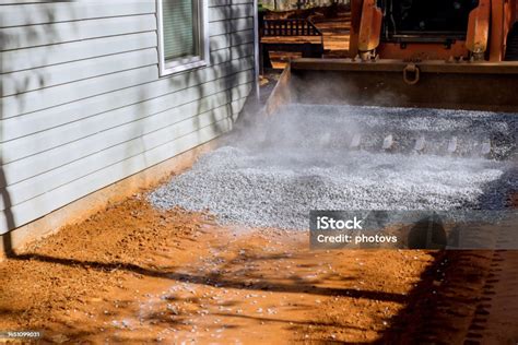 건설 현장의 수리 도로 공사의 일환으로 로더 굴삭기를 사용하여 쇄석을 하역했습니다 프론트 엔드 로더에 대한 스톡 사진 및 기타