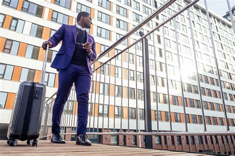 성공적이고 잘 차려 입은 아프리카 계 미국인 사업가가 바퀴 달린 가방을 들고 공항에서 비행기를 타기 위해 걷는 전체 길이 초상화 바퀴 달린 대형 여행 가방 25 29세에