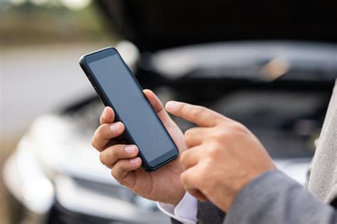 젊은 아시아 사업은 자동차를 분해했다 그는 후드를 열고 엔진을 확인합니다 그는 도움과 서비스를 위해 스마트 폰 을 호출합니다