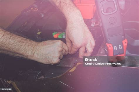 자동차 서비스 수리 튜닝 유지 보수의 개념 자동차 전기 기사는 자동차 전자 장치의 문제를 해결합니다 자동차 클로즈업에서 전기 장치로 작업하는 전기 기술자의 손 가린 얼굴에