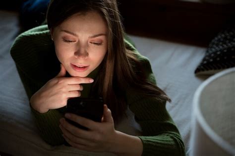 그녀의 스마트 폰을 보면서 침대에 누워있는 여자 무료 사진