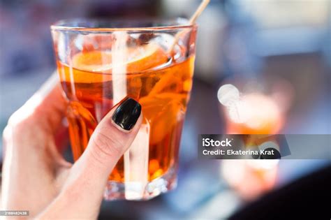 화창한 날에 오렌지 스프레이가 뿌려진 유리 검은 손톱을 가진 여성의 손 야외에서 음료를 제공합니다 격리 개념 전통적인 베네치아 이탈리안 칵테일 축하 컨셉입니다 스피릿 테이크