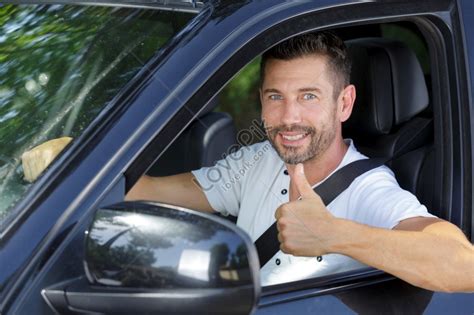 그의 새 차를 운전하는 동안 엄지손가락을 치켜세우고 웃는 성공적인 남자 사진 무료 다운로드 Lovepik