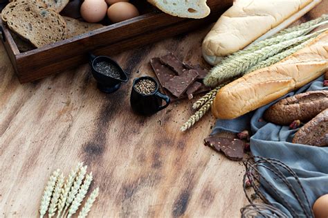 조식 및 구운된 빵 개념입니다 신선한 향기로운 빵 그리고 나무 테이블에 알입니다 신선한 빵과 커피 나무 검은 배경에 밀 키 위 고 초콜릿입니다 컵에 참 깨 씨앗입니다 갈색에
