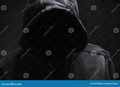 Unrecognizable Cyber Criminal Or Computer Hacker Wearing Black Hooded Jacket Low Key Portrait