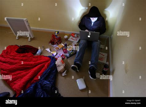 computer user hacker sits conspiratorially in an empty apartment