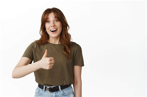 Возбужденная молодая женщина показывает палец вверх и счастлива улыбается дает положительный