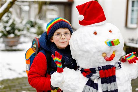 화려한 옷을 입은 어린 학교 소년 초등학교 졸업 후 눈사람과 함께 재미있는 안경과 배낭 남학생에 대한 스톡 사진 및 기타 이미지