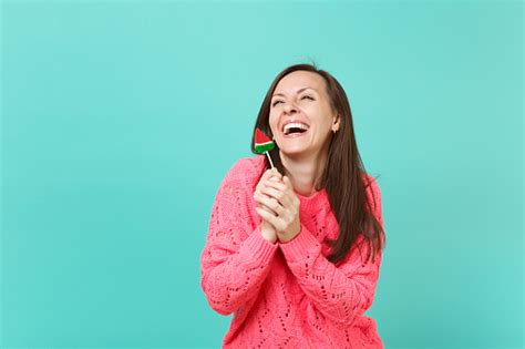 찾고 블루 터키석 벽 배경 스튜디오 초상화에 고립 된 수 박 사탕을 들고 니트 핑크 스웨터에 웃음 재미 있은 젊은 여자 사람들의 라이프 스타일 개념입니다 복사 공간을 비웃는