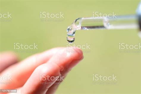 아름 다운 여자의 손 떨어지는 세럼 콜라겐 보습제 얼굴의 명확한 노란색 병 부드러운 빛 배경 프로텍터 스킨 트리트먼트 페이셜 에센스 오일 건강관리와 의술에 대한 스톡 사진