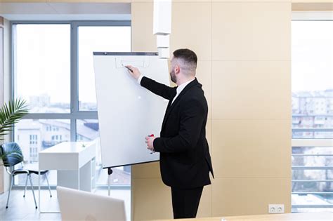 젊은 잘 생긴 사업가 통신 화상 통화를 수행 컨퍼런스 회의 온라인 작동 노트북을 사용 플립 차트에 쓰기 설명합니다 카메라를 보고 미소 짓는다 25 29세에 대한 스톡 사진