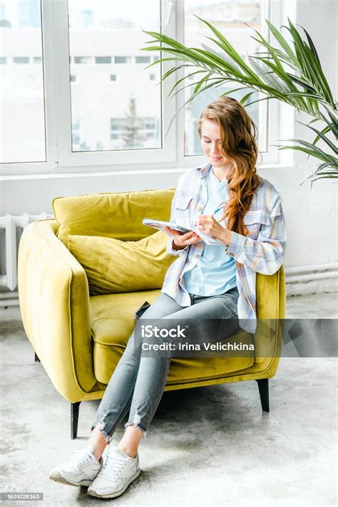 공책이 있는 캐주얼 셔츠를 입은 젊은 아름다운 긴 머리 대학생 소녀 노란 의자에 앉아 있는 주최자 펜 메모를 하는 여성 사업가 프리랜서 원격 작업 심리 일기의 기록 25