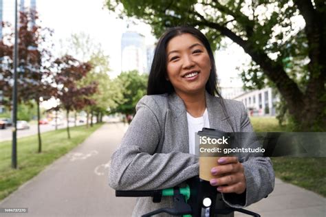 비즈니스 복장을 하고 커피 한 잔을 들고 전기 스쿠터를 타고 서 있는 중국 여성의 초상화 거리에 대한 스톡 사진 및 기타 이미지 거리 도시 도시 거리 Istock