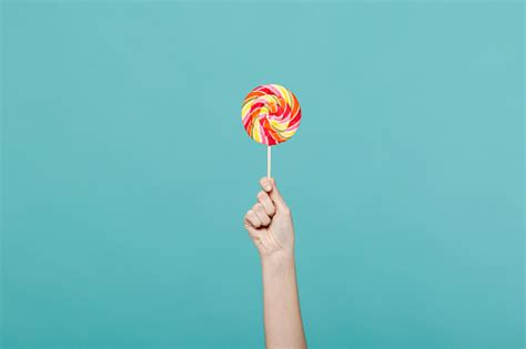 가까이 여자 손에 들고 다채로운 라운드 롤리팝 파란색 청록색 벽 배경에 고립 적절 한 영양 또는 과자 디저트 패스트 푸드 다이어트 아침 개념입니다 광고 공간을 복사 합니다
