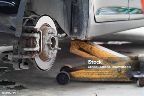 수리를 위해 차량의 디스크 브레이크 누출 자동차 타이어를 밀봉 차고에서 자동차 브레이크 수리 더러운 노란색 유압 잭 지게차 수리 차에 대한 스톡 사진 및 기타 이미지