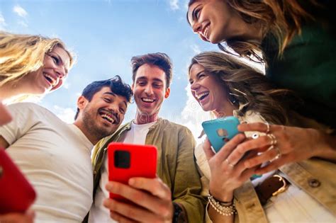 Group Of Young People Using Mobile Phones Against Blue Sky Stock Image