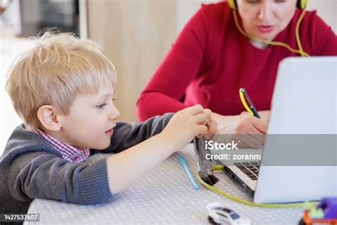 테이블에 앉아서 초콜릿 바를 여는 유아 헤드폰이 켜져있는 노트북에서 일하는 어머니 2 3 살에 대한 스톡 사진 및 기타 이미지