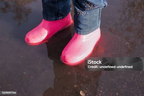 웅덩이에 서있는 레인 부츠에 아이의 다리 가을에 아이들 가을 산책 중 분홍색 고무 부츠를 입은 아기 소녀 다리를 클로즈업합니다 아이들은 야외에서 즐거운 시간을 보내고