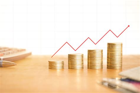 사무실 책상 위에 황금 돈 동전 더미가 있고 그래프와 빨간색 위쪽 화살표가 있습니다 비즈니스 및 금융 개념 개념에 대한 스톡