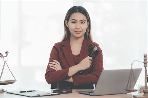 여성 변호사 또는 판사가 문서나 계약서를 확인하고 수첩에 메모를 하고 법률 사무소에서 망치와 저울을 들고 노트북을 옆에 두고 일하고 있습니다 Conference On The