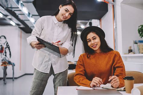 실내에서 브레인 스토밍 세션 동안 함께 협력 하는 아름 다운 성공적인 여성 직원의 절반 길이 초상화 공동 작업에서 프로젝트에 작업 하는 동안 카메라를 보고 여자 가장 친한