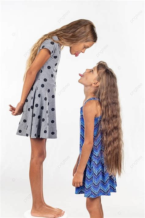 Two Girls Playfully Stick Out Their Tongues While One Stands On Chair