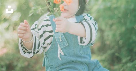 오렌지 꽃을 들고 모자를 쓰고 있는 소녀 사진 Unsplash의 무료 꽃 이미지