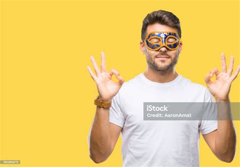 격리 된 배경 위에 잘생긴 젊은이 입고 카니발 마스크 휴식과 명상 손가락으로 제스처를 하 고 폐쇄 눈으로 웃 고 요가 개념